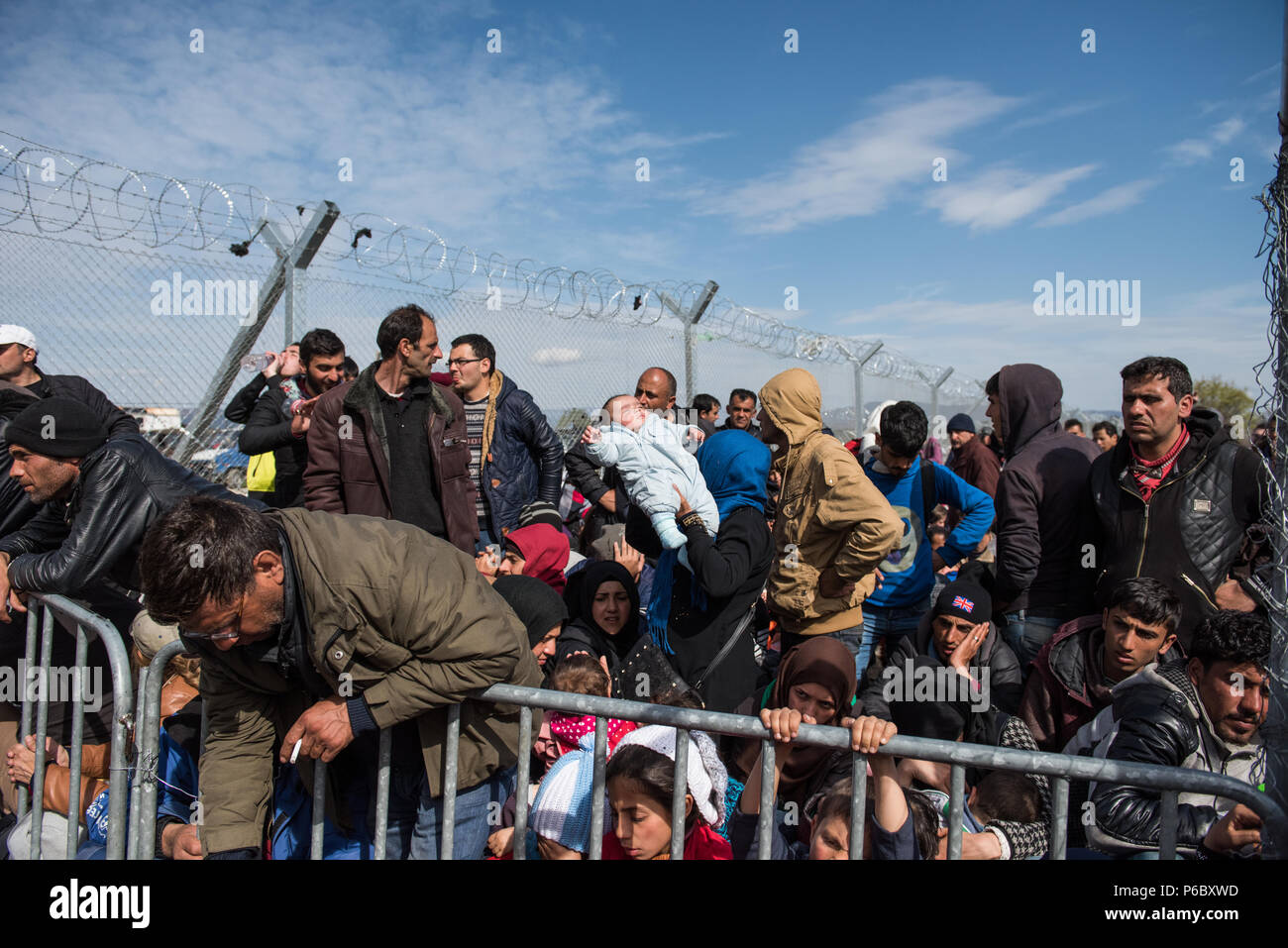 Refugee gather beside the barbed wire close to the gate as they wait to ...