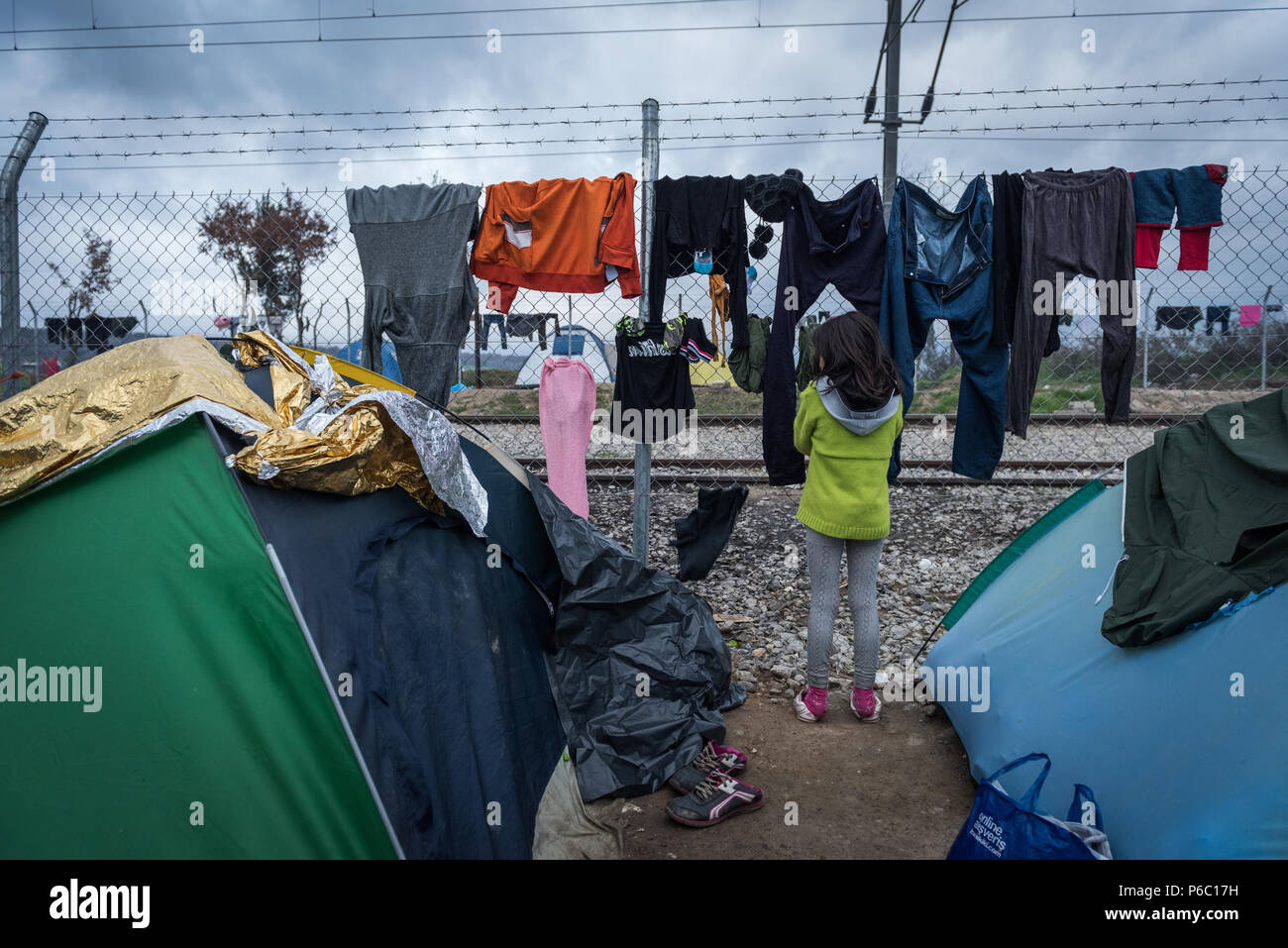 A refugee girl looks through wire mesh in a makeshift refugee camp at ...