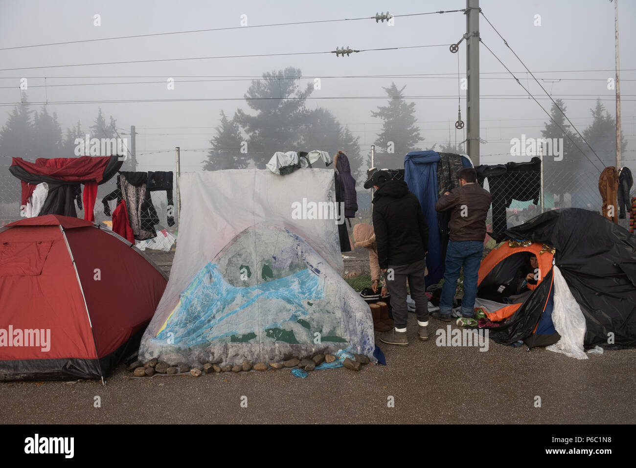 Refugees hangs their clothes at barbed wire between tents at the train ...
