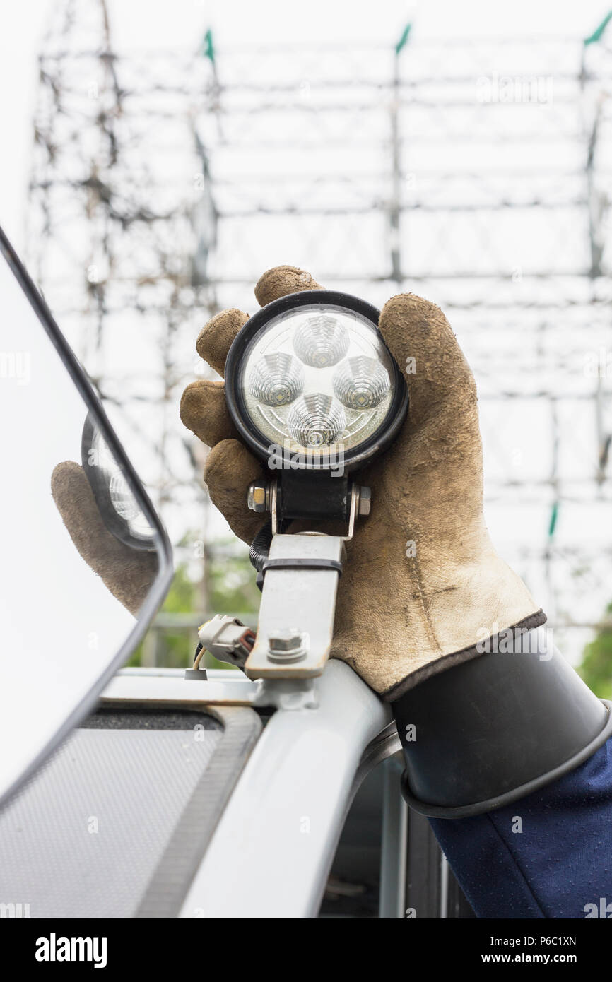 Engineer adjusting work light on vehicle Stock Photo - Alamy