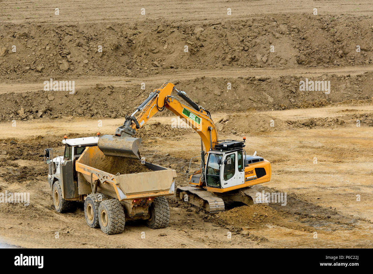 JCB digger moving soil into back of large truck at quarry Stock Photo ...