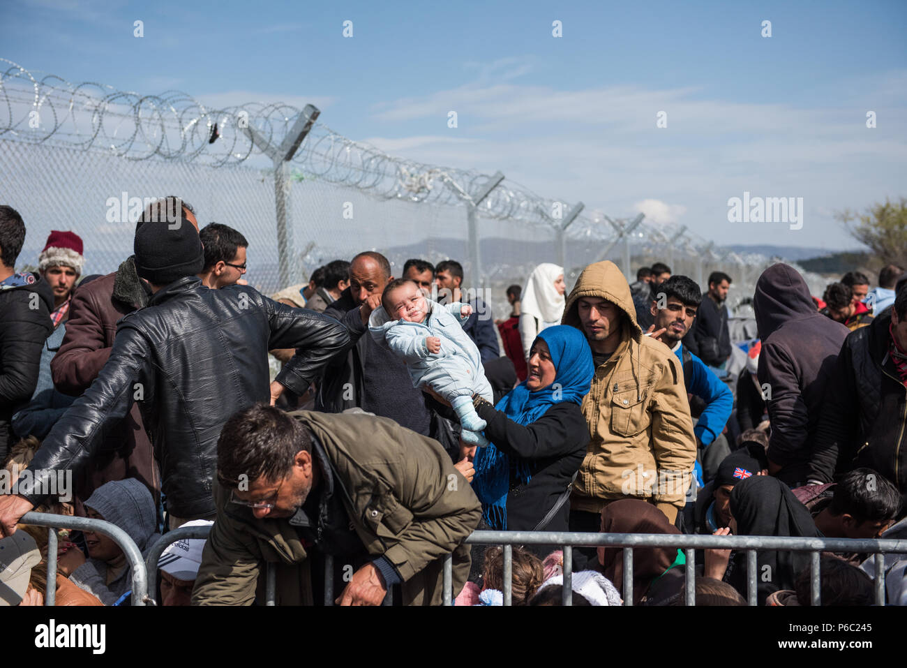 Refugee gather beside the barbed wire close to the gate as they wait to ...