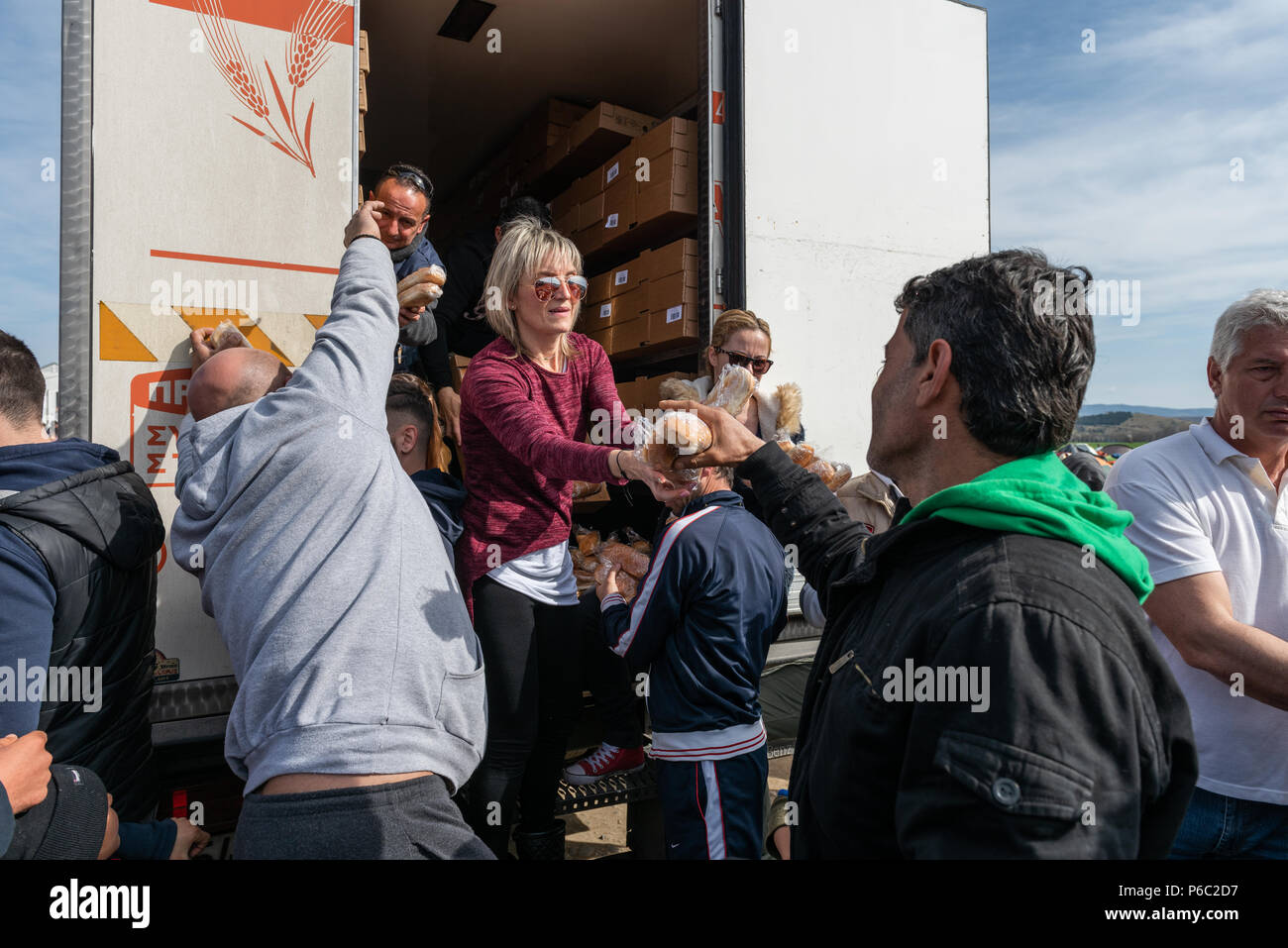 Refugees wait in the queue for a distribution of food at the makeshift ...