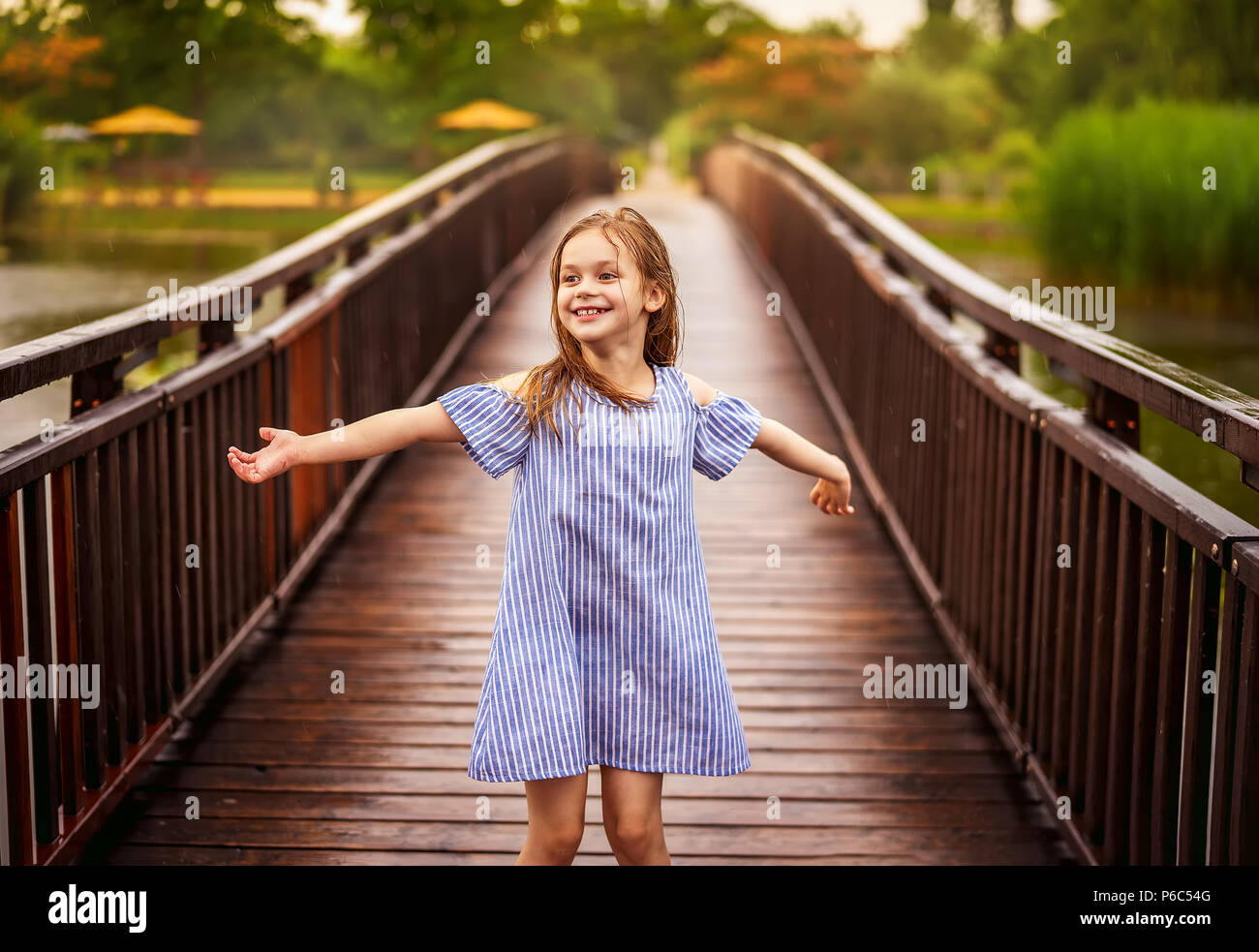 Little girl playing outdoors under summer rain Stock Photo - Alamy