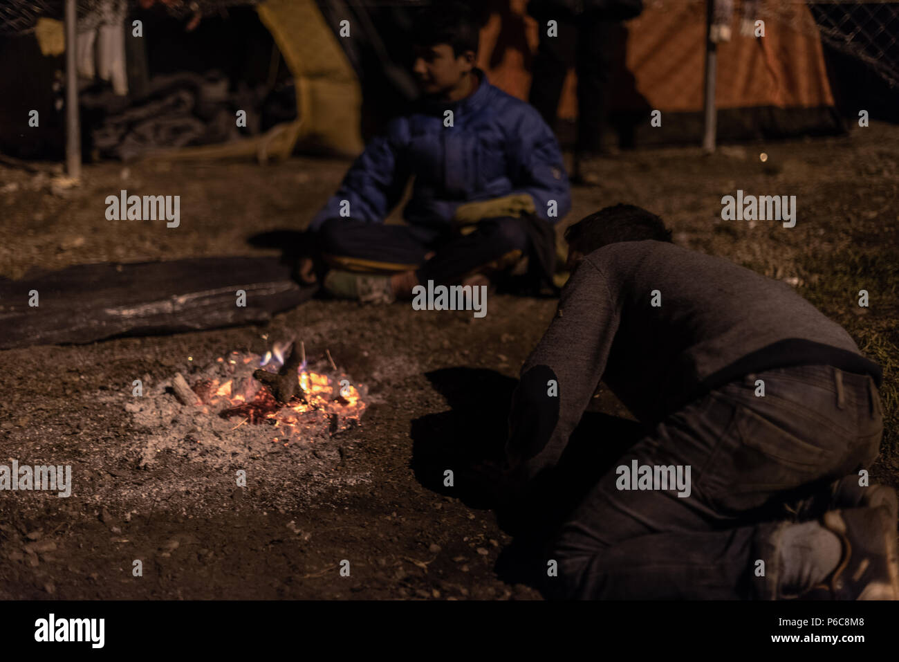 Refugee try to warm themselves by a bonfire at the night at the ...