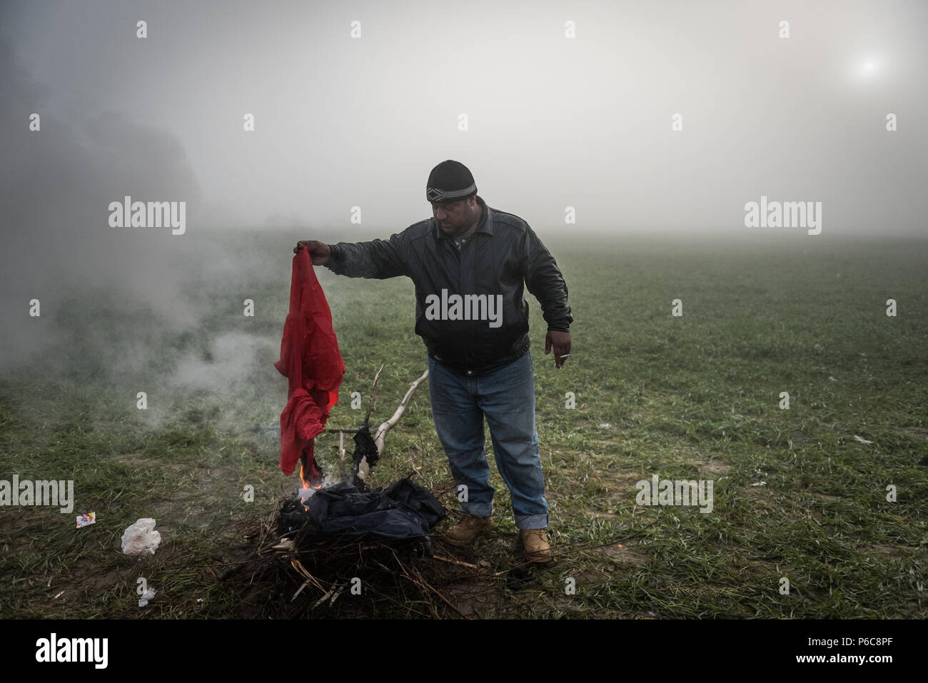 A man burns a jacket to make it a bonfire during a foggy morning of the ...