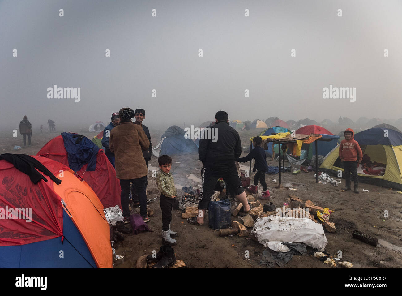 People gather around a bonfire at the makeshift refugee camp of the ...