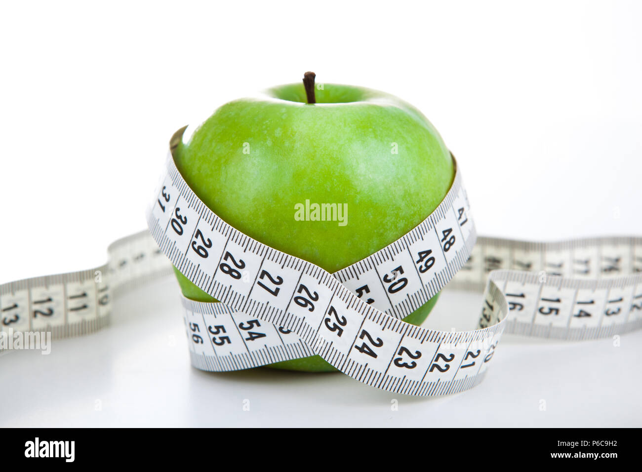 green apple with a ruler on a white background Stock Photo - Alamy