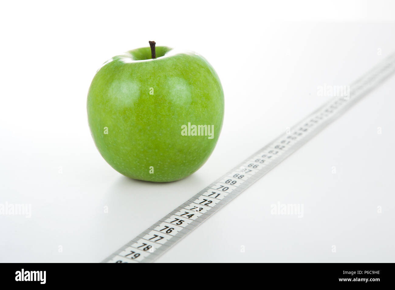 green apple with a ruler on a white background Stock Photo - Alamy