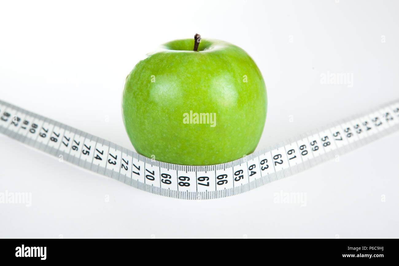 green apple with a ruler on a white background Stock Photo - Alamy