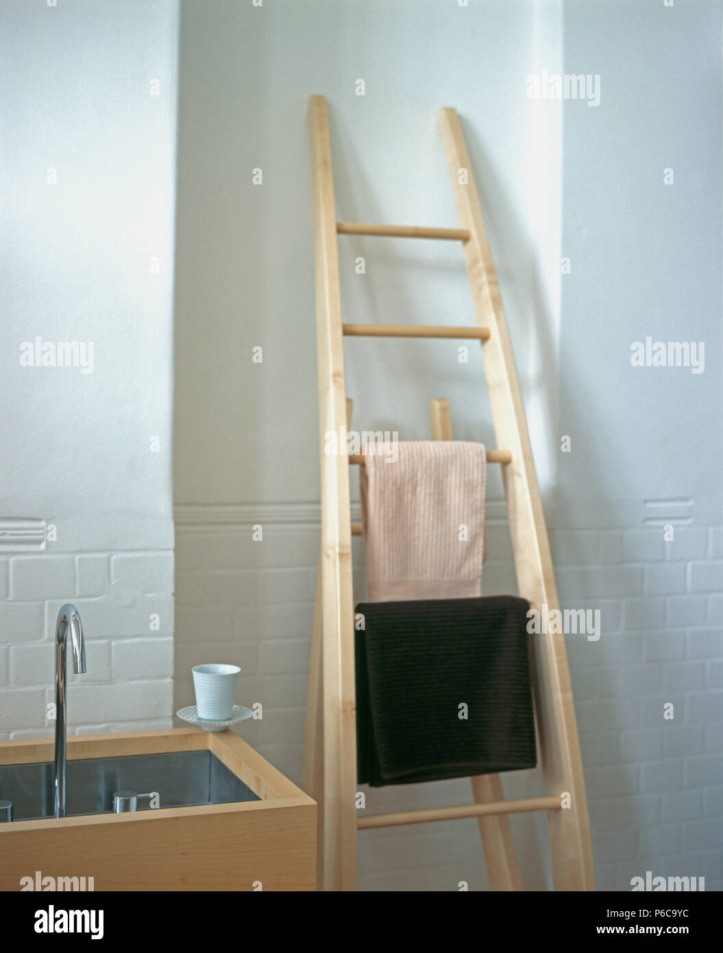 Towels on wooden ladder beside zinc-lined wooden basin in modern ...