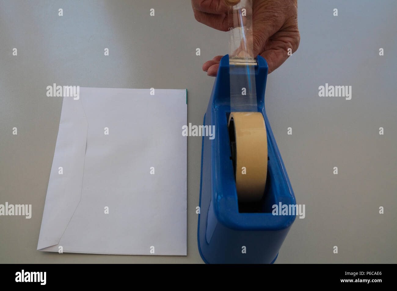 Tearing a piece of sticky tape off a roll in a tape dispenser to seal a ...