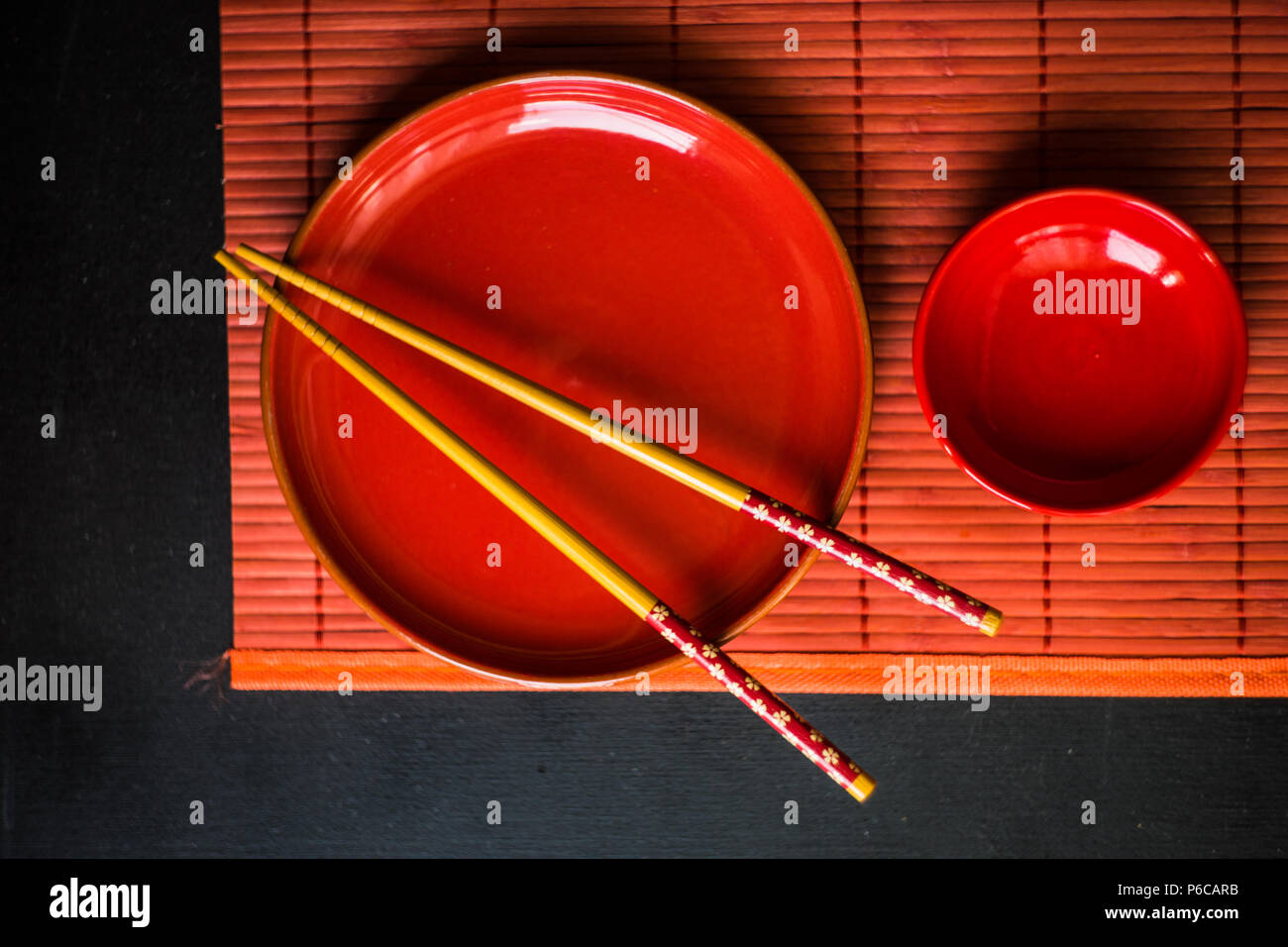 Table setting in red color for asian cuisine dinner with chopsticks ...