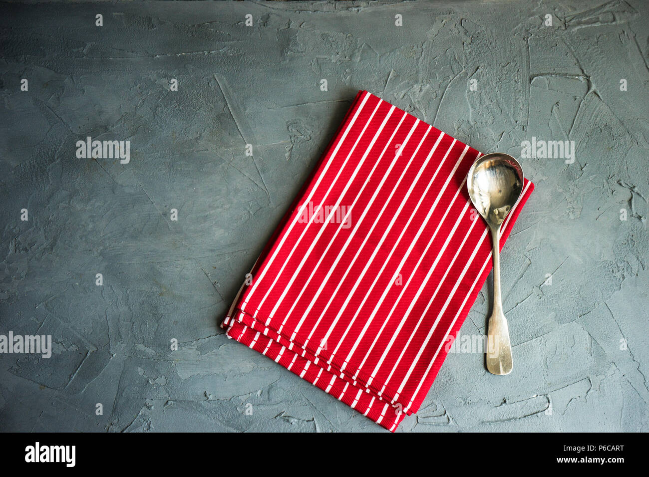 Red stripped napkin and spoon as a cooking concept on concrete ...