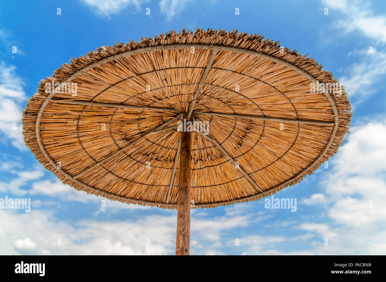 Straw umbrella against blue cloudy sky background close Stock Photo - Alamy