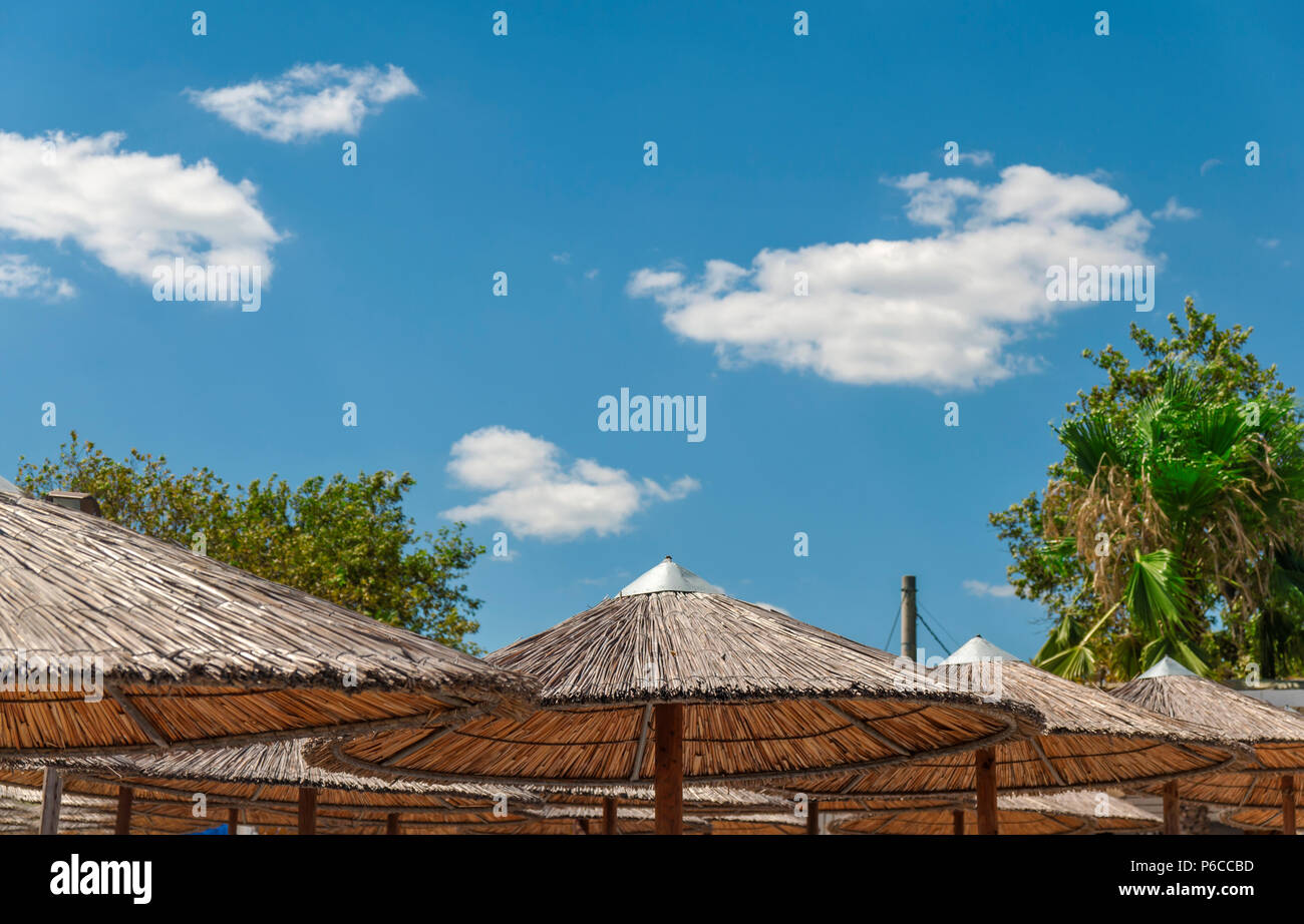 Umbrella straw and blue cloudy sky background Stock Photo - Alamy