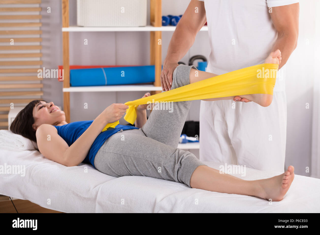 Physiotherapist Giving Leg Treatment To Woman With Yellow Exercise Band ...