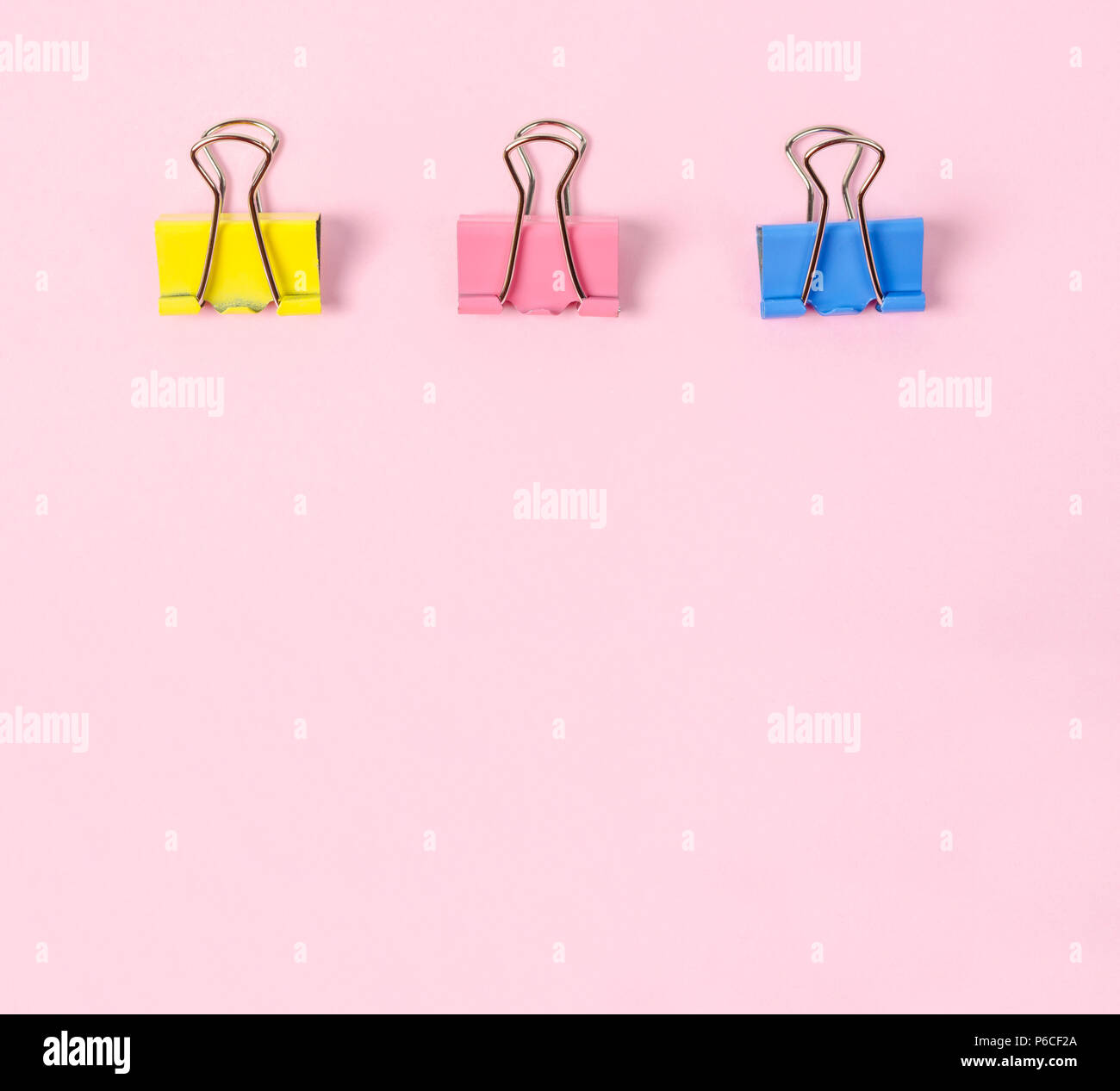 Colorful binder clips on pink background with free space for your text ...