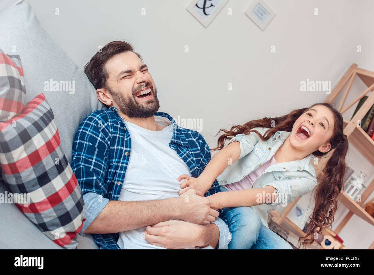 Father and little daughter at home lying girl tickling father screaming ...