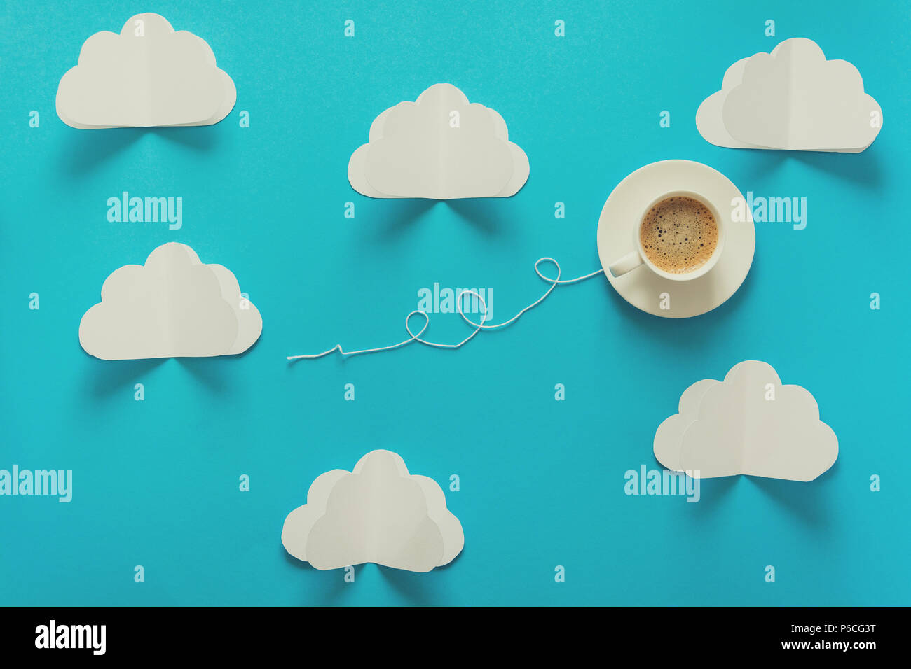 Coffee cup in shape of balloon with cllouds on blue paper background ...