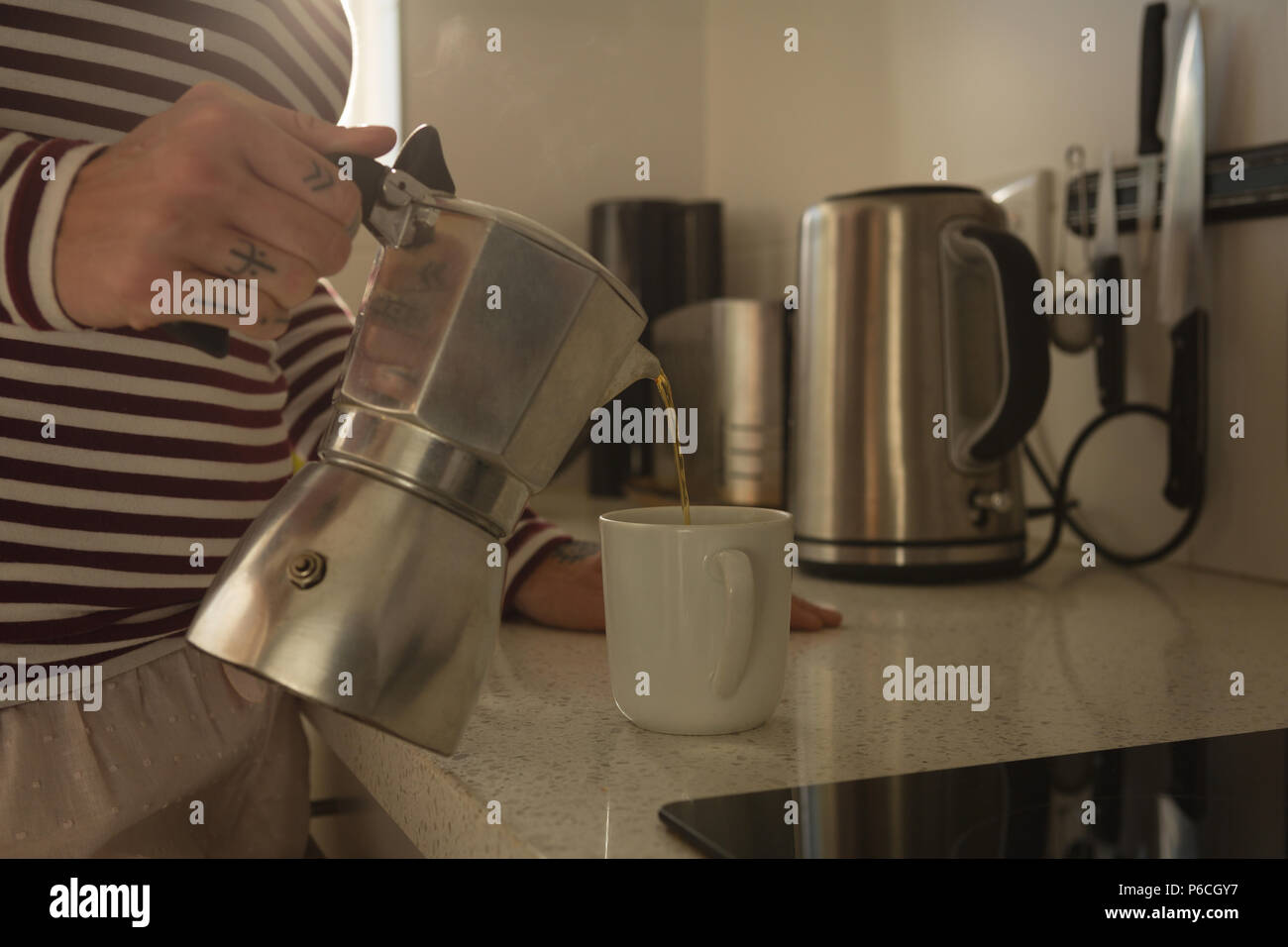 Woman pouring coffee into mug in kitchen Stock Photo - Alamy