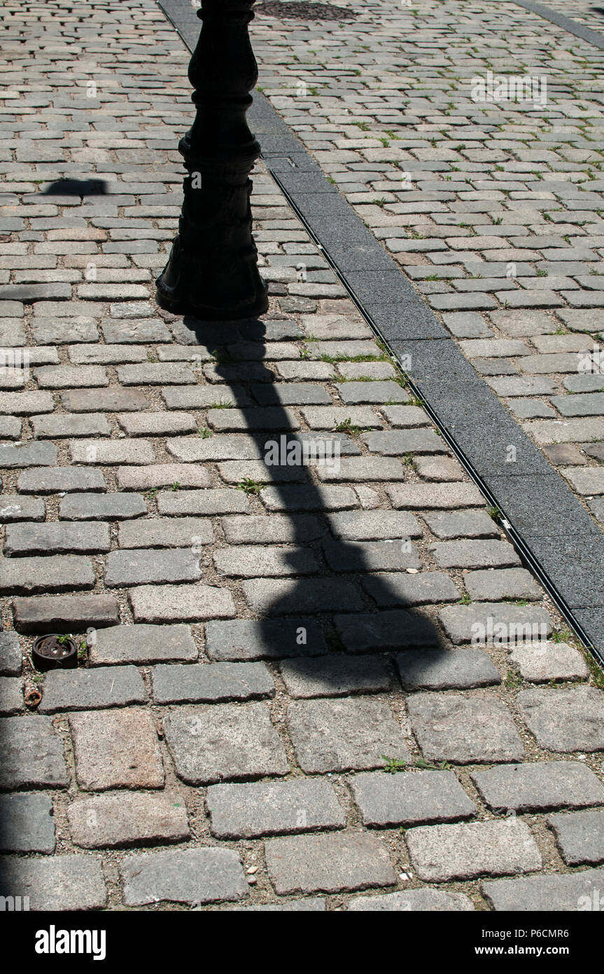 Old retro street light pillar shadow on city gray stone paved street ...