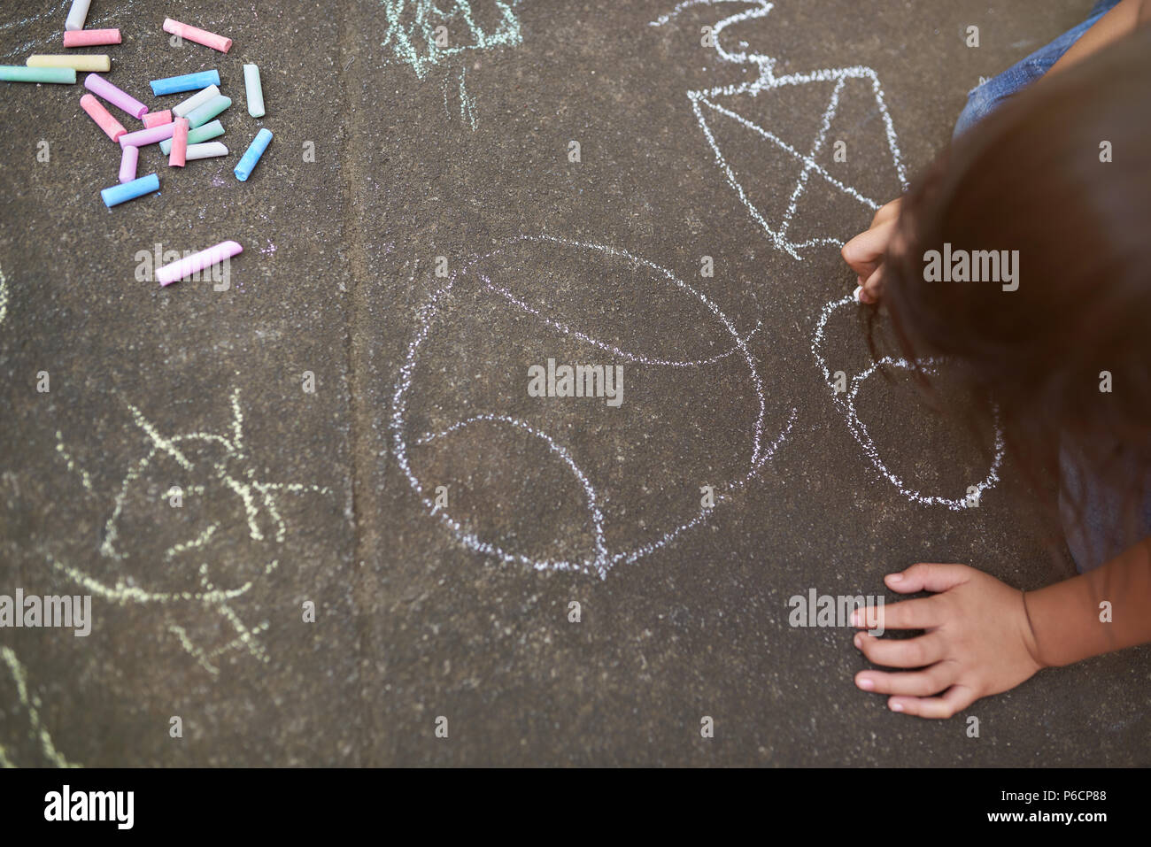 Small kid drawing on asphalt above top view Stock Photo - Alamy