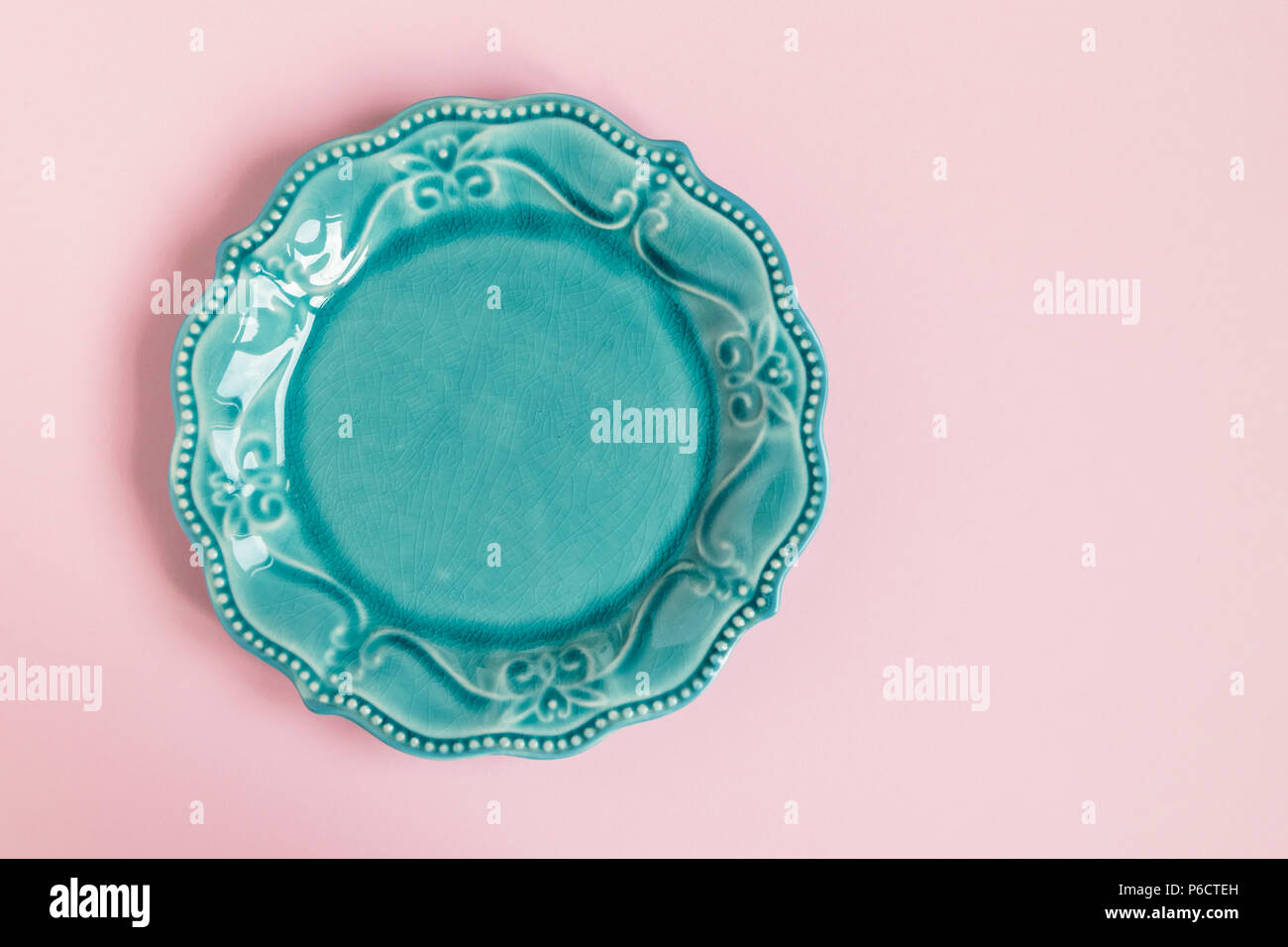Cyan rustic empty plate on a pink pastel background. Plate on the left ...
