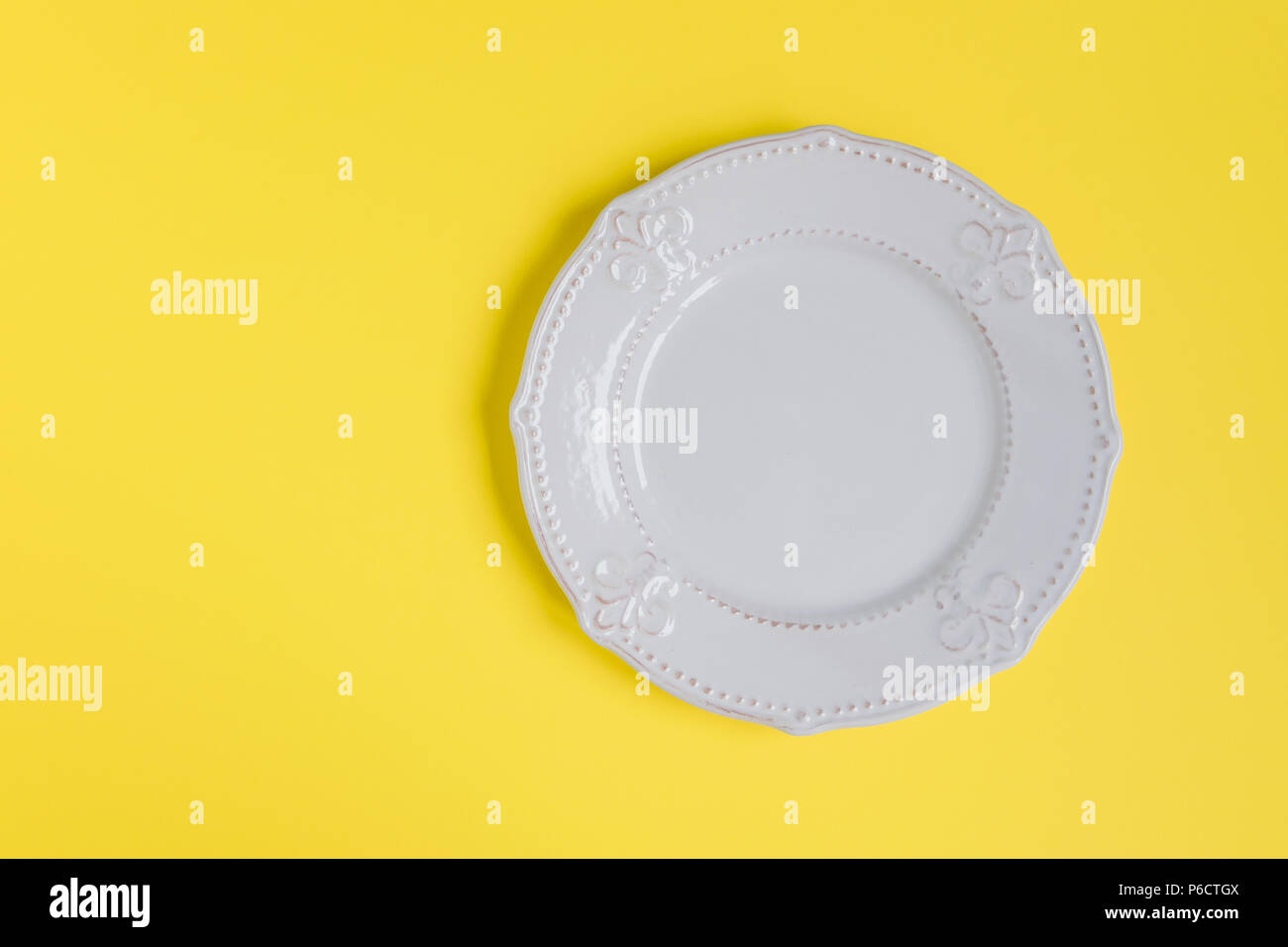 White rustic plate on yellow background. Plate on the right side of ...