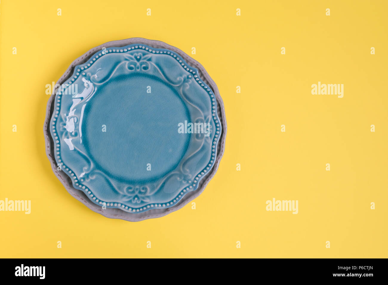 Two rustic plates on yellow background. Plates on left side of frame ...