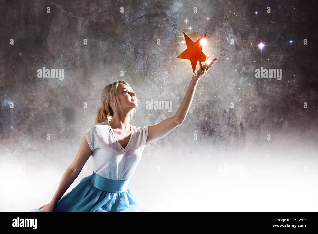 Young attractive woman reaching for the star. Take a star from the sky ...