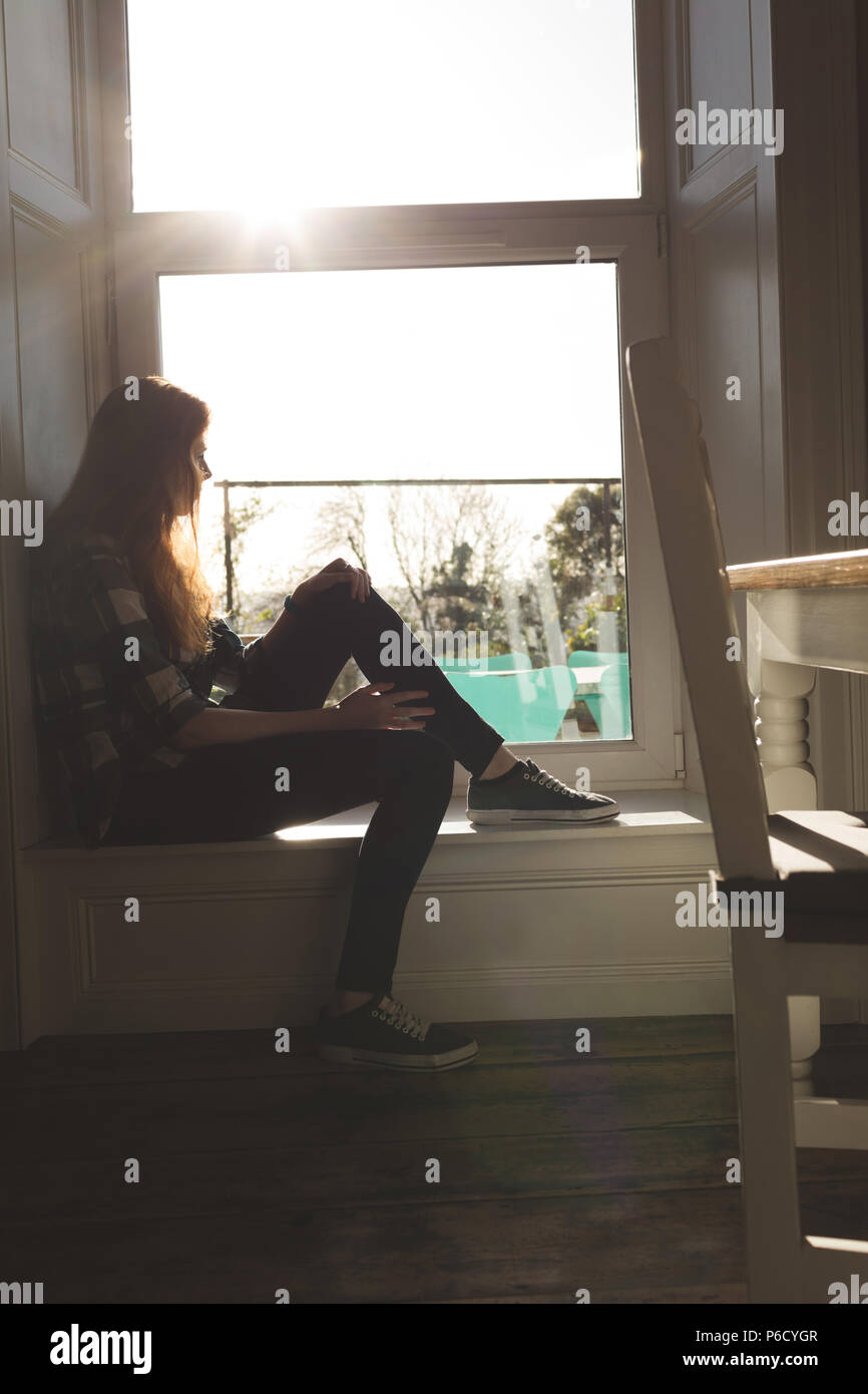Woman siting near window at home Stock Photo - Alamy