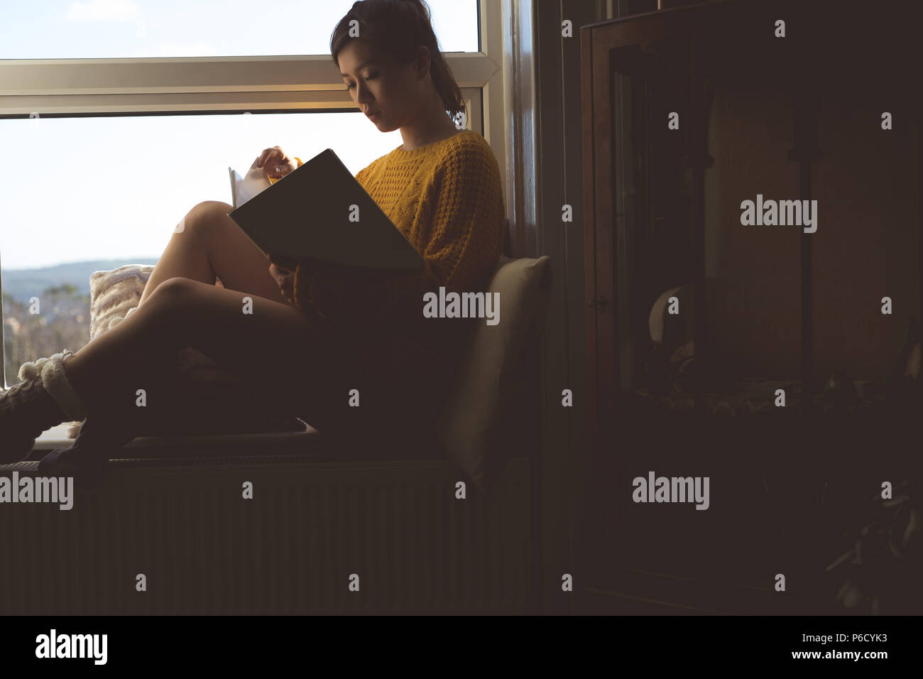 Woman reading a book at the window hi-res stock photography and images ...