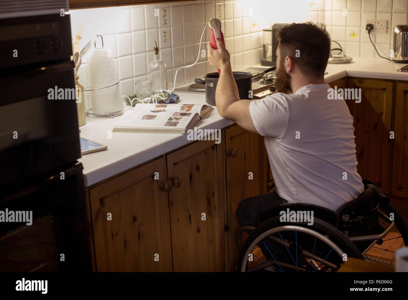 Disabled man repairing a pan in kitchen Stock Photo - Alamy