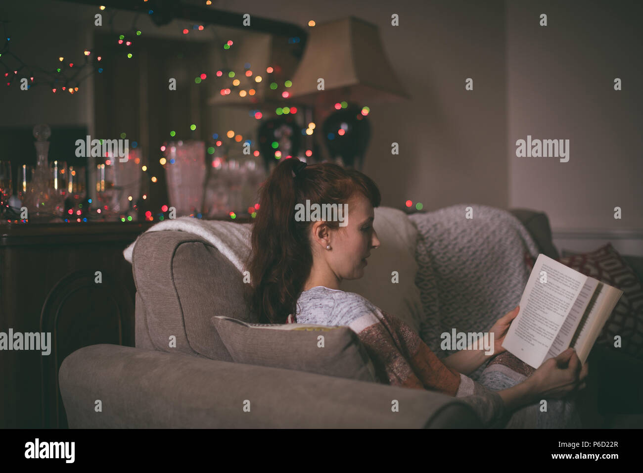 Woman reading a book in living room Stock Photo - Alamy