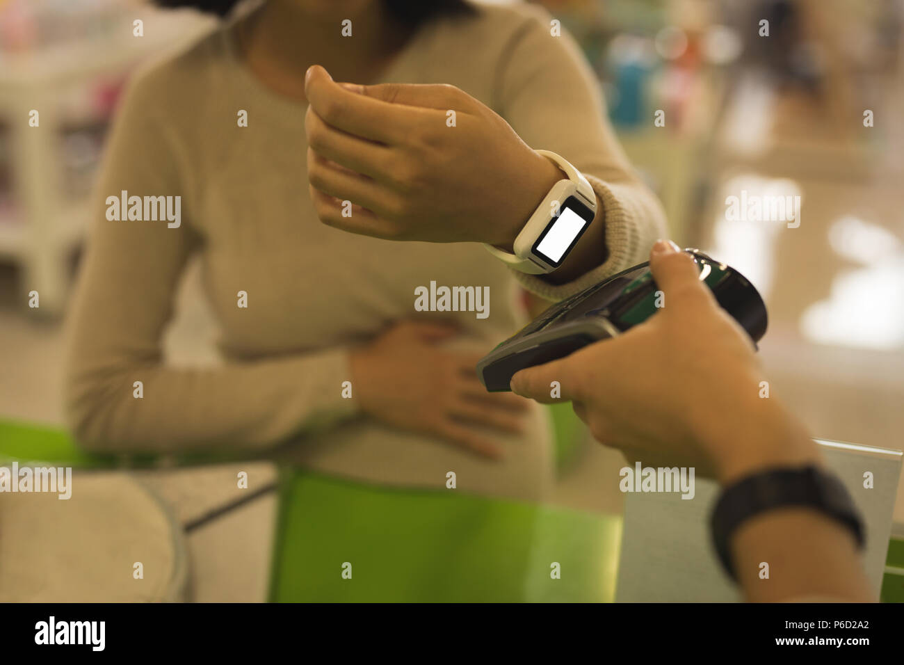 Pregnant woman making payment through smartwatch Stock Photo - Alamy