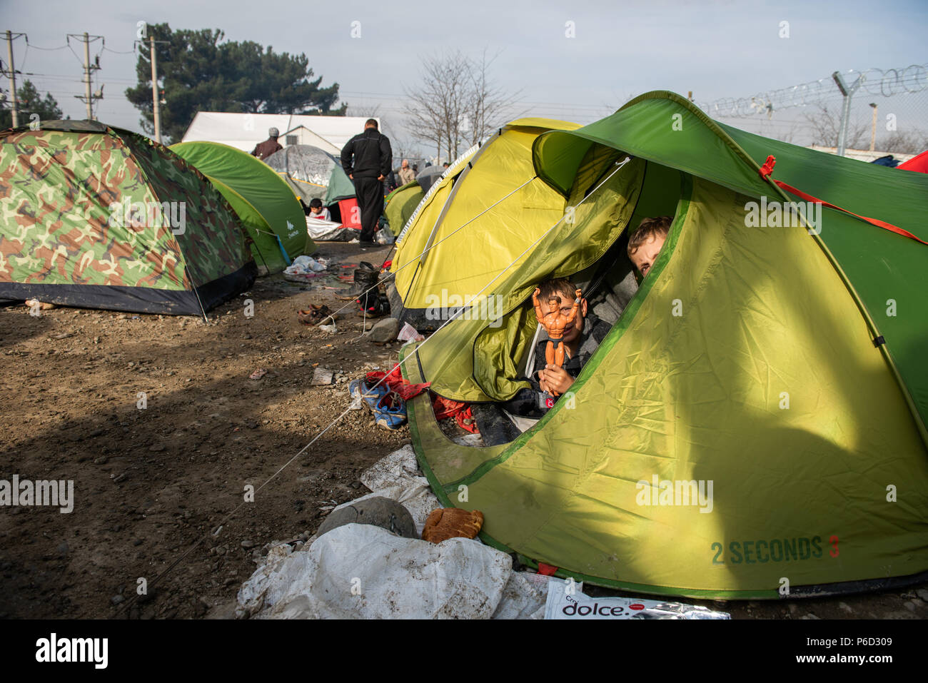 A young children looks out from a tent at the makeshift camp of the ...