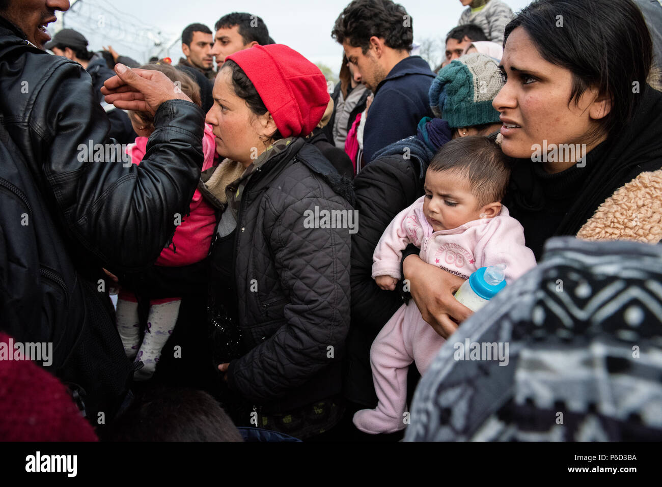 A refugee mother close to the border gate holds her child a as she and ...