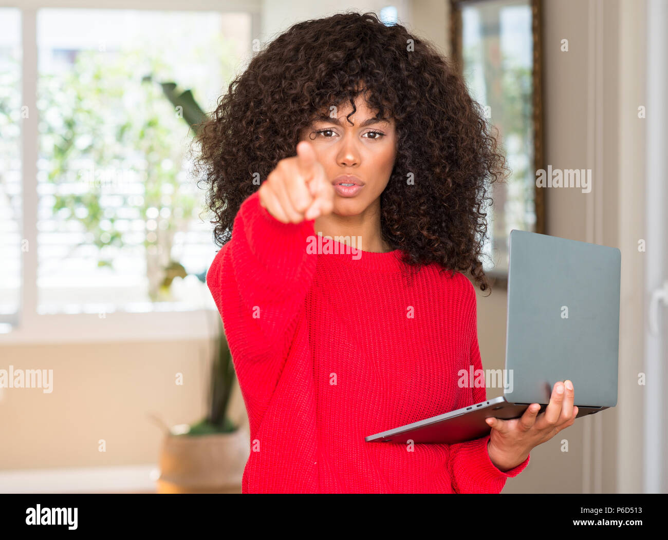 African american woman standing using computer laptop at home pointing ...
