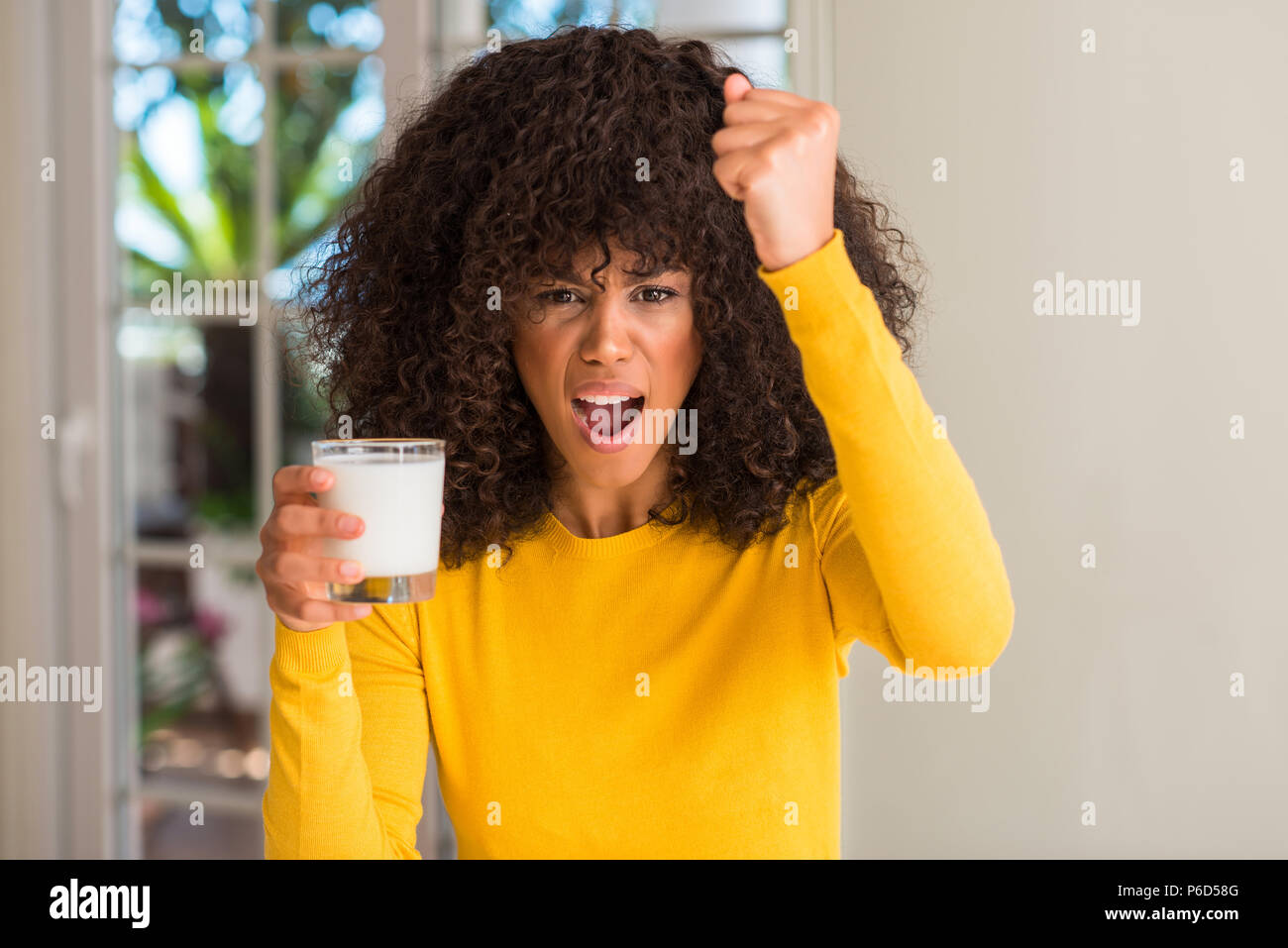 African american woman holding a glass of milk annoyed and frustrated ...