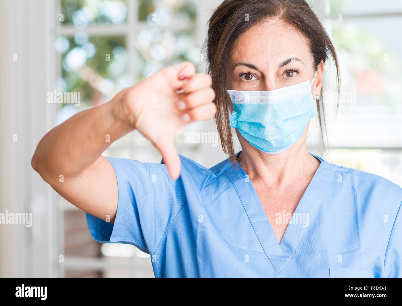 Middle aged doctor woman with angry face, negative sign showing dislike ...