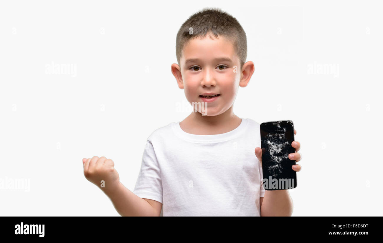 Dark haired little child holding broken smartphone screaming proud and ...