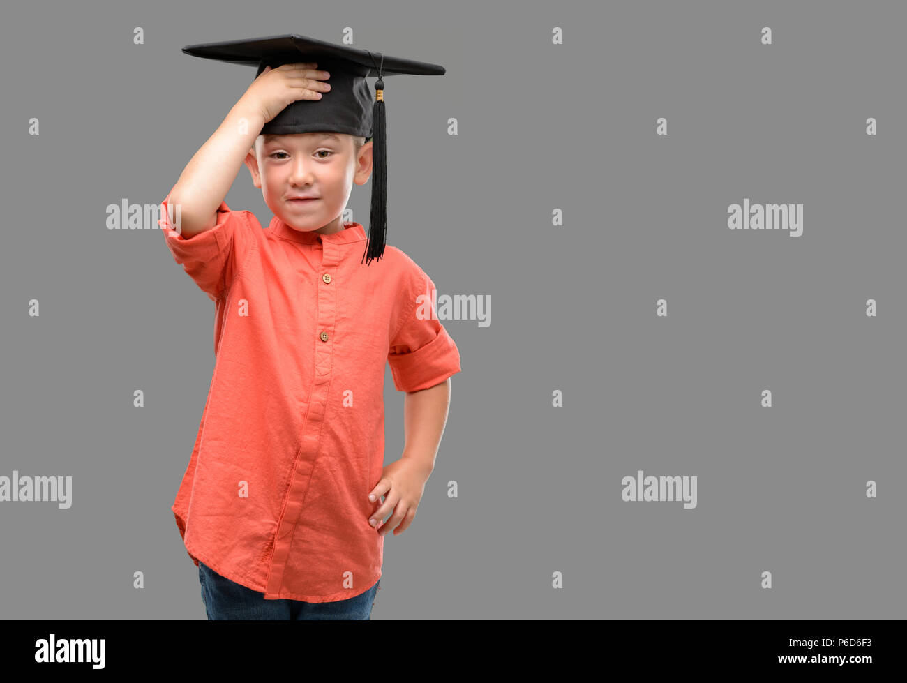 Dark haired little child wearing graduation cap stressed with hand on ...