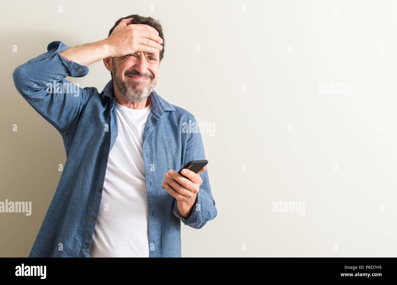 Senior man using smartphone stressed with hand on head, shocked with ...