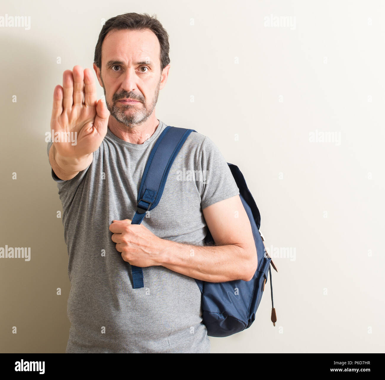 Senior man using backpack with open hand doing stop sign with serious ...