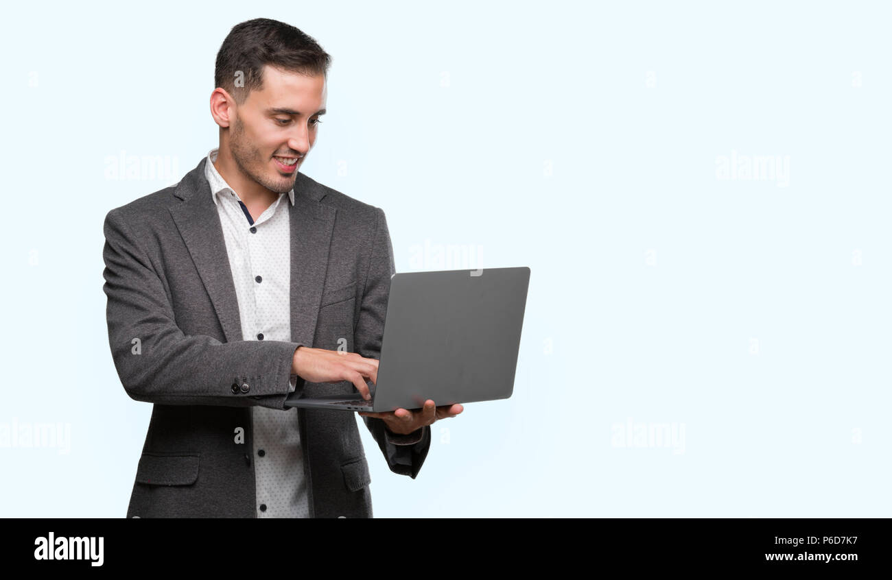 Handsome young man using computer laptop with a happy face standing and ...