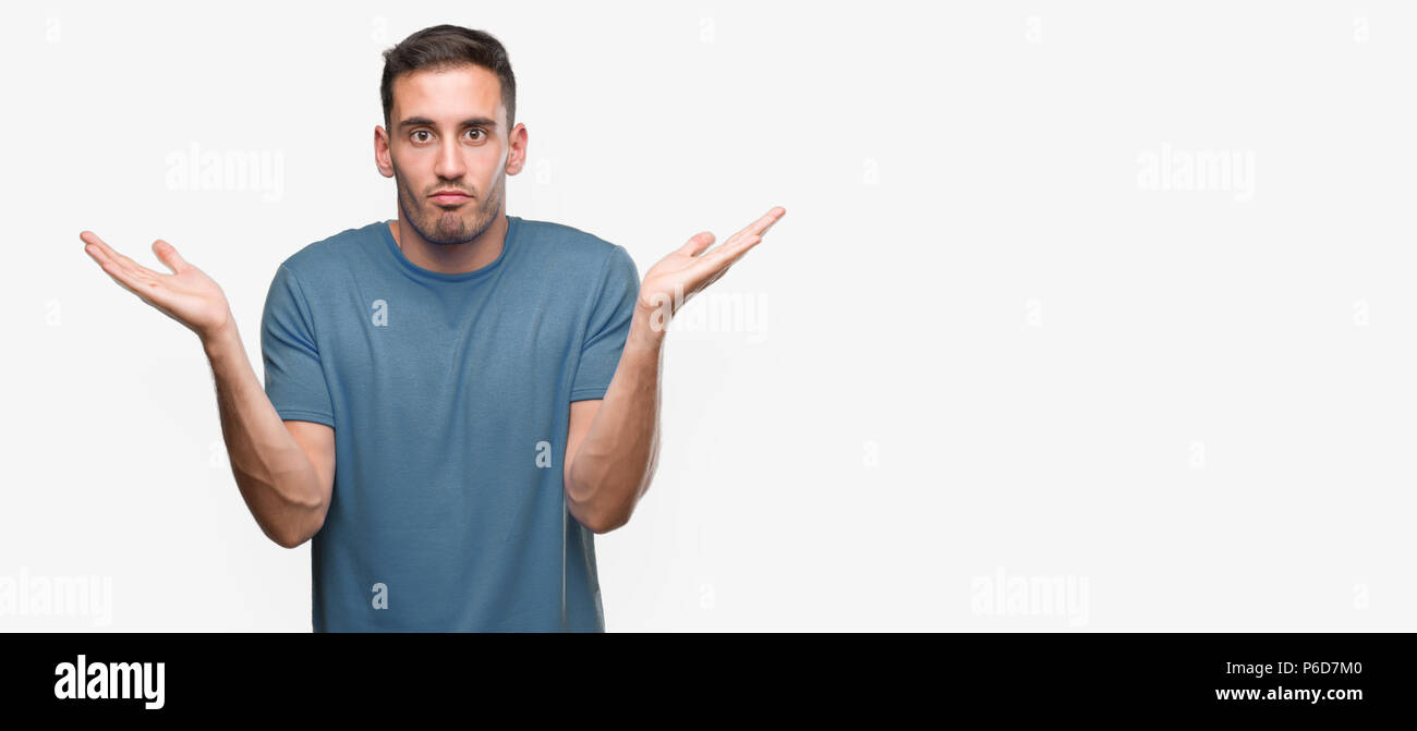 Handsome young casual man clueless and confused expression with arms ...