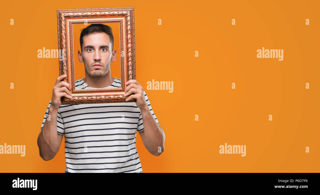 Handsome young man looking through vintage art frame with a confident ...