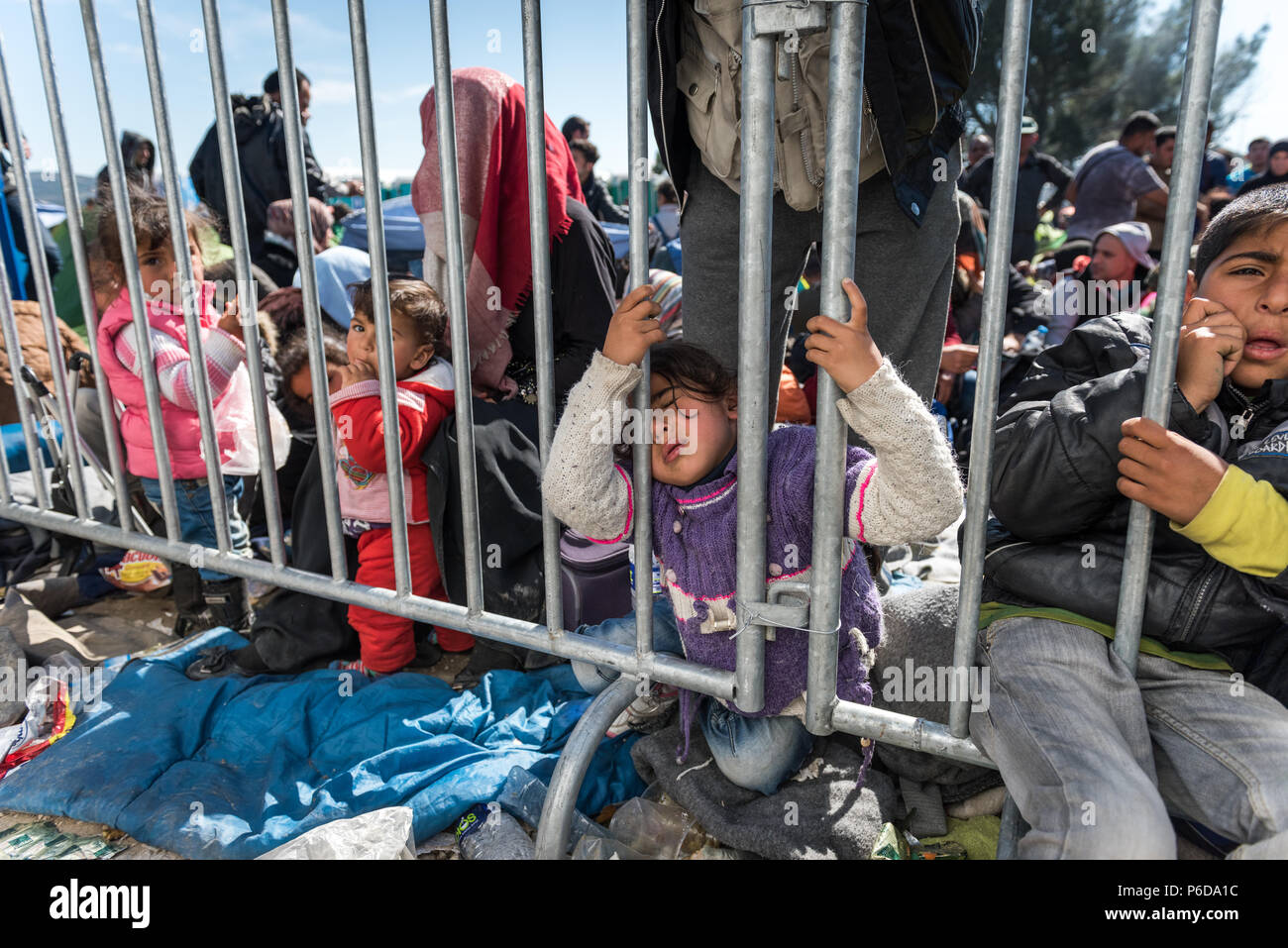 Children sleep behind railings close to the gate as they wait to cross ...