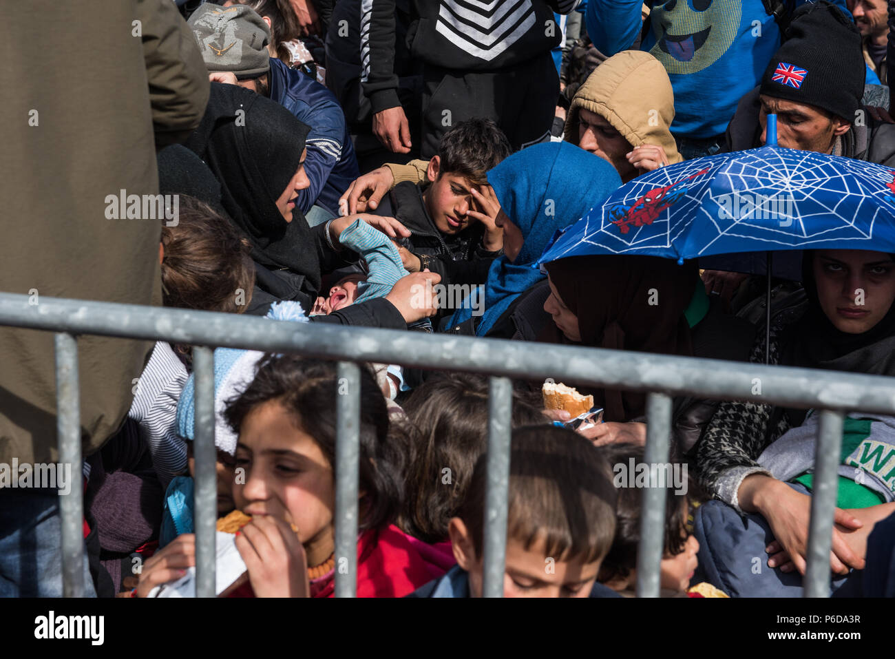 Refugee gather behind railings close to the gate as they wait to cross ...